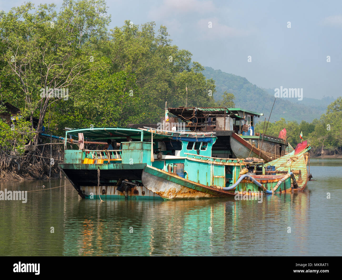 Rusty cargo vessel at a canal cutting through the mangrove forest on ...
