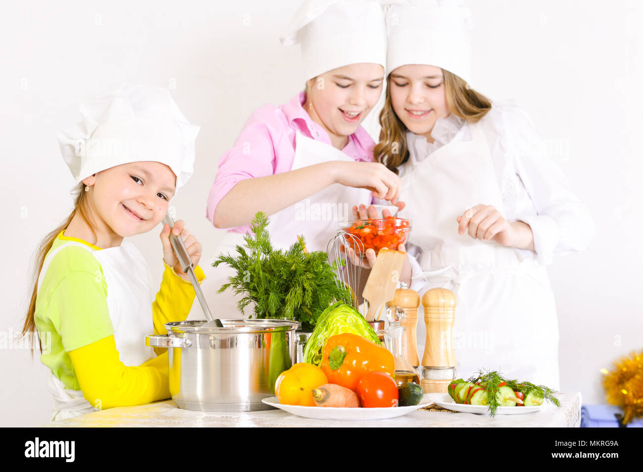 Cute little girls in chef's hats and aprons preparing dinner in the ...