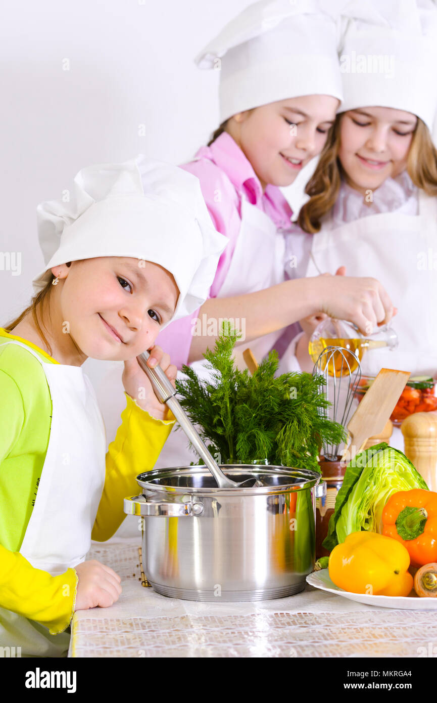 Cute little girls in chef's hats and aprons preparing dinner in the ...