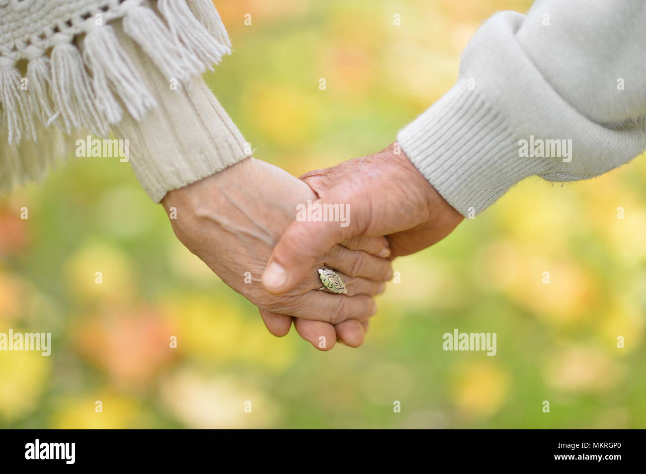 Elderly couple holding hands together in autumn park Stock Photo - Alamy