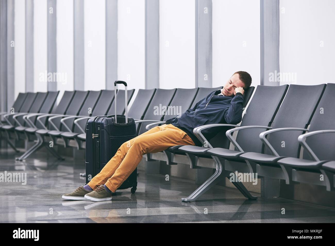 Man traveling by airplane. Tired passenger sleeping in airport terminal ...