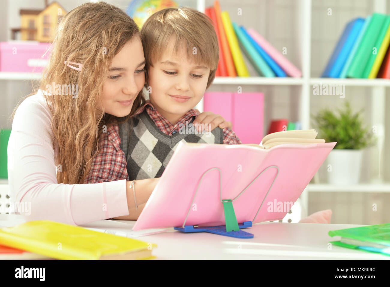 Teenage girl helping her little brother with homework Stock Photo - Alamy