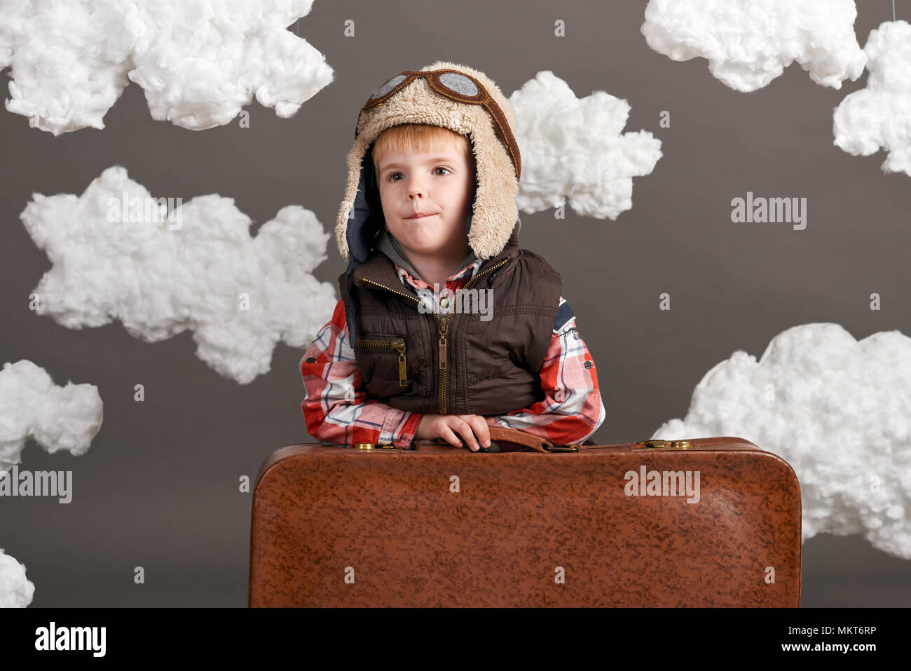boy dressed as an airplane pilot stand between the clouds with old ...