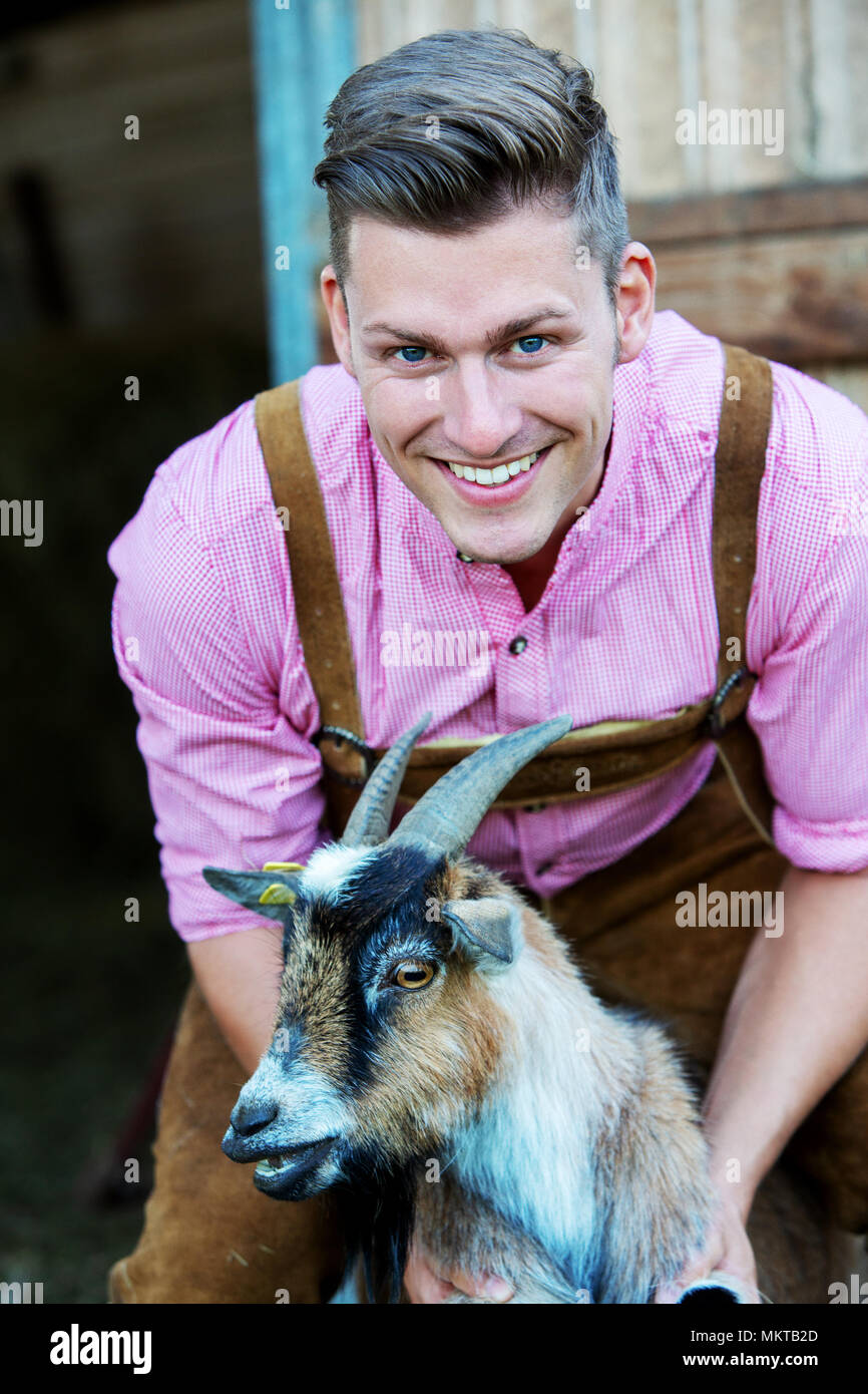 portrait of young bavarian man holding a goat Stock Photo - Alamy