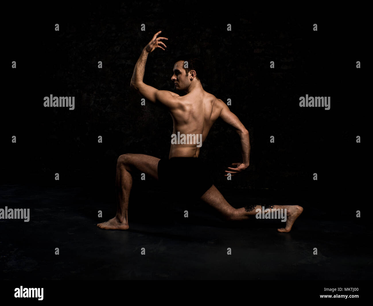 Modern ballet dancer in black shorts performing artdance element with ...