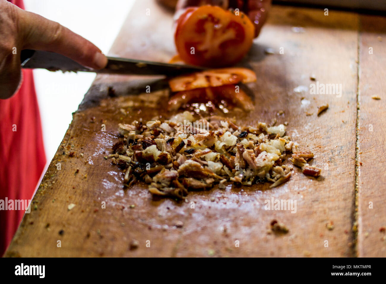 Man is preparing kokorec (fried sheep bowel) with tomato and spices ...