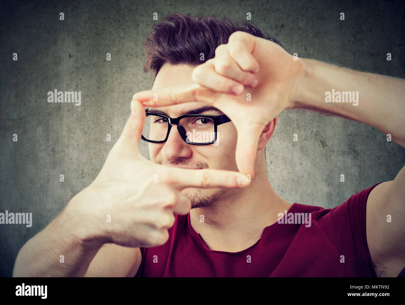 Young man making frame with hands creating shot and looking at camera ...