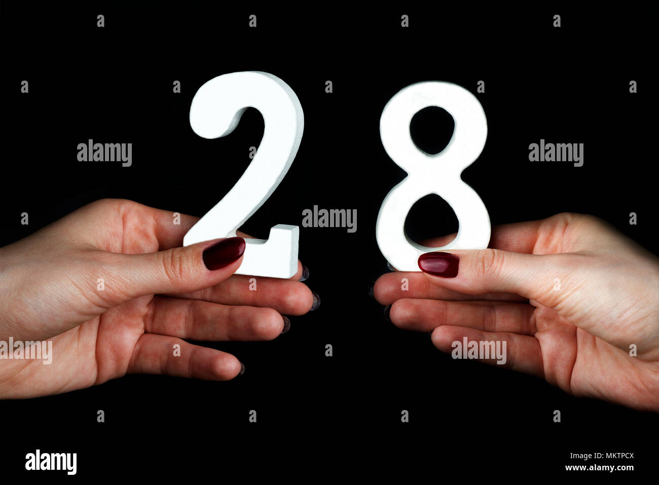 On a black background, female hand with number twenty-eight Stock Photo ...