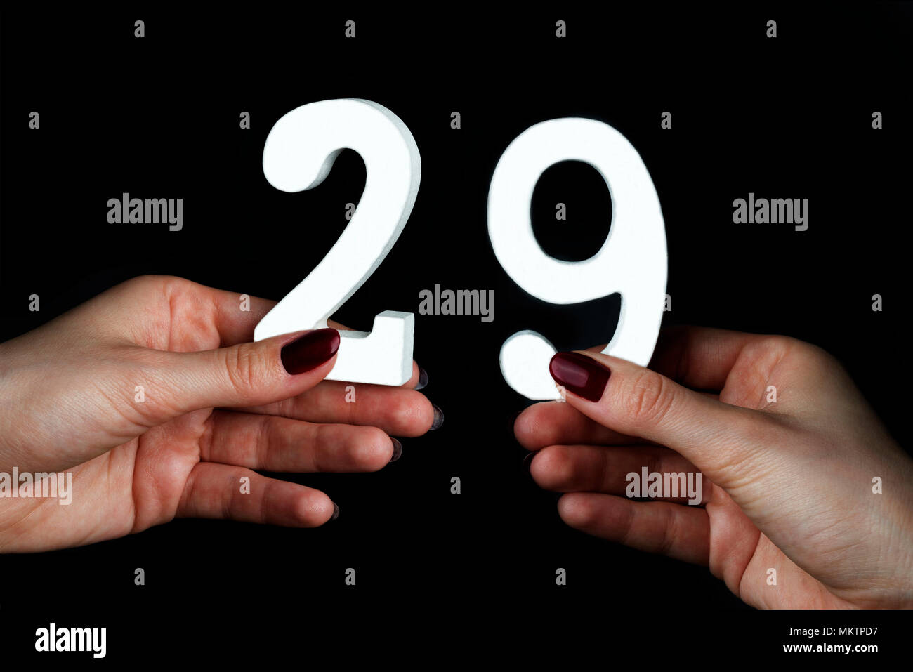On a black background, female hand with number twenty-nine Stock Photo ...