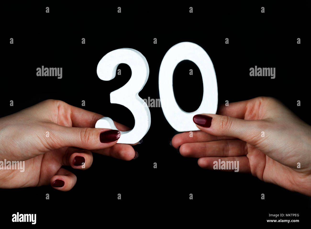 On a black background, female hand with a figure thirty Stock Photo - Alamy