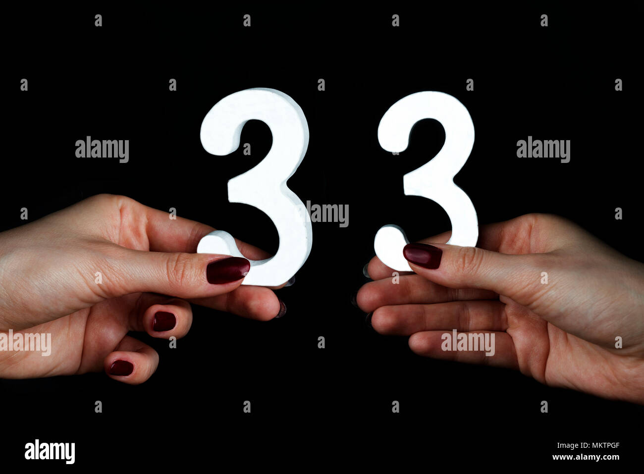 On a black background, female hand with the number thirty-three Stock ...