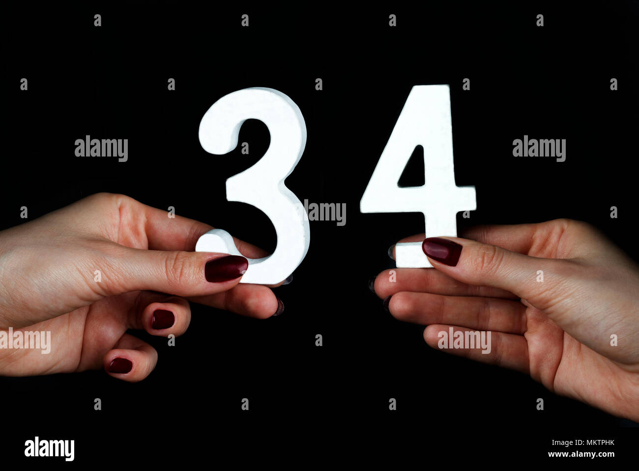 On a black background, female hand with number thirty-four Stock Photo ...