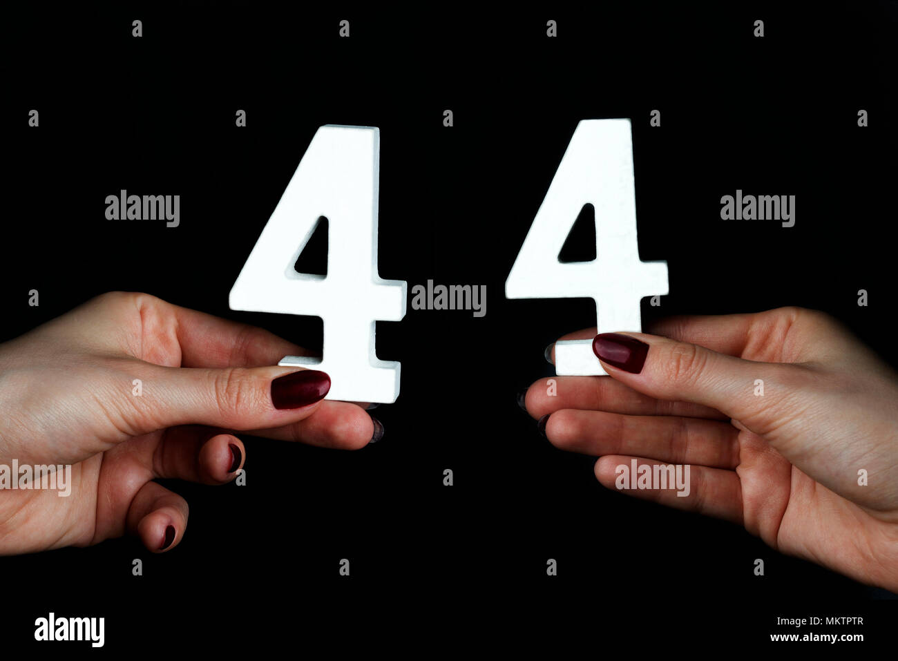 On a black background, female hand with number forty-four Stock Photo ...