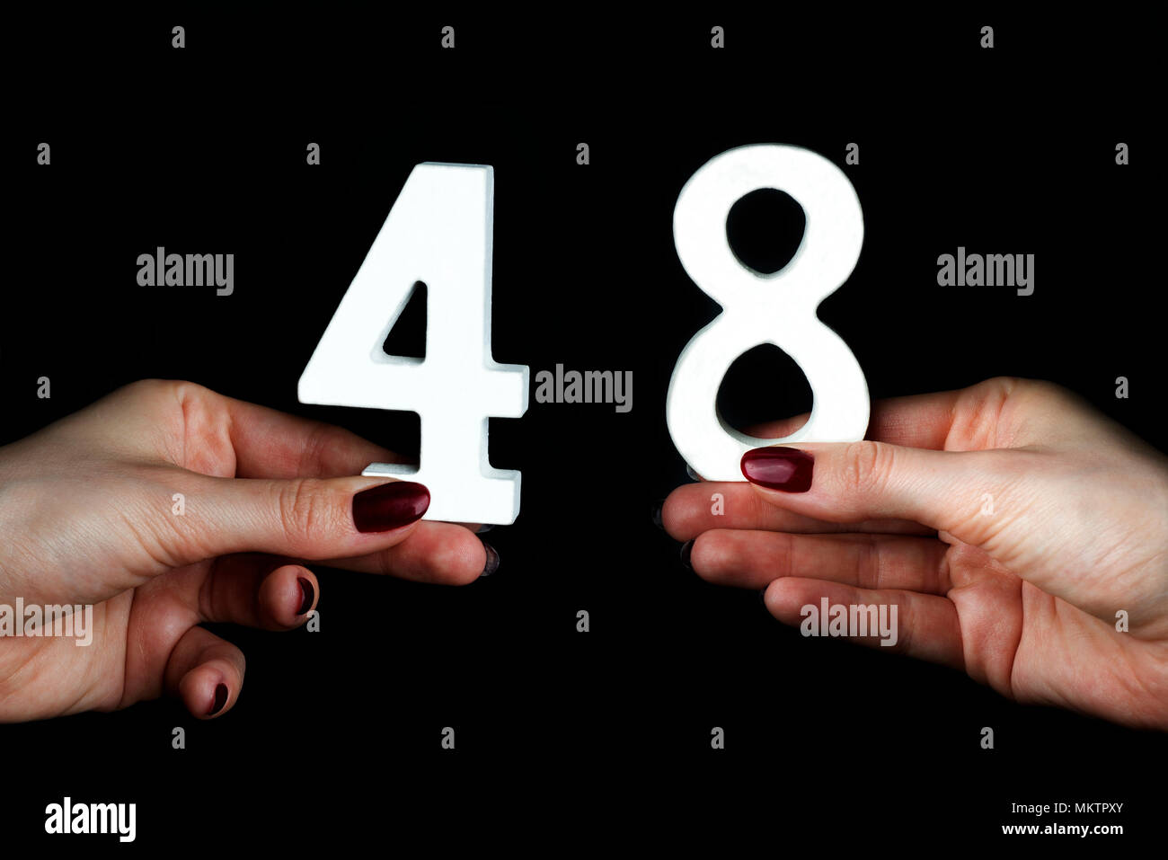 On a black background, female hand with number forty-eight Stock Photo ...