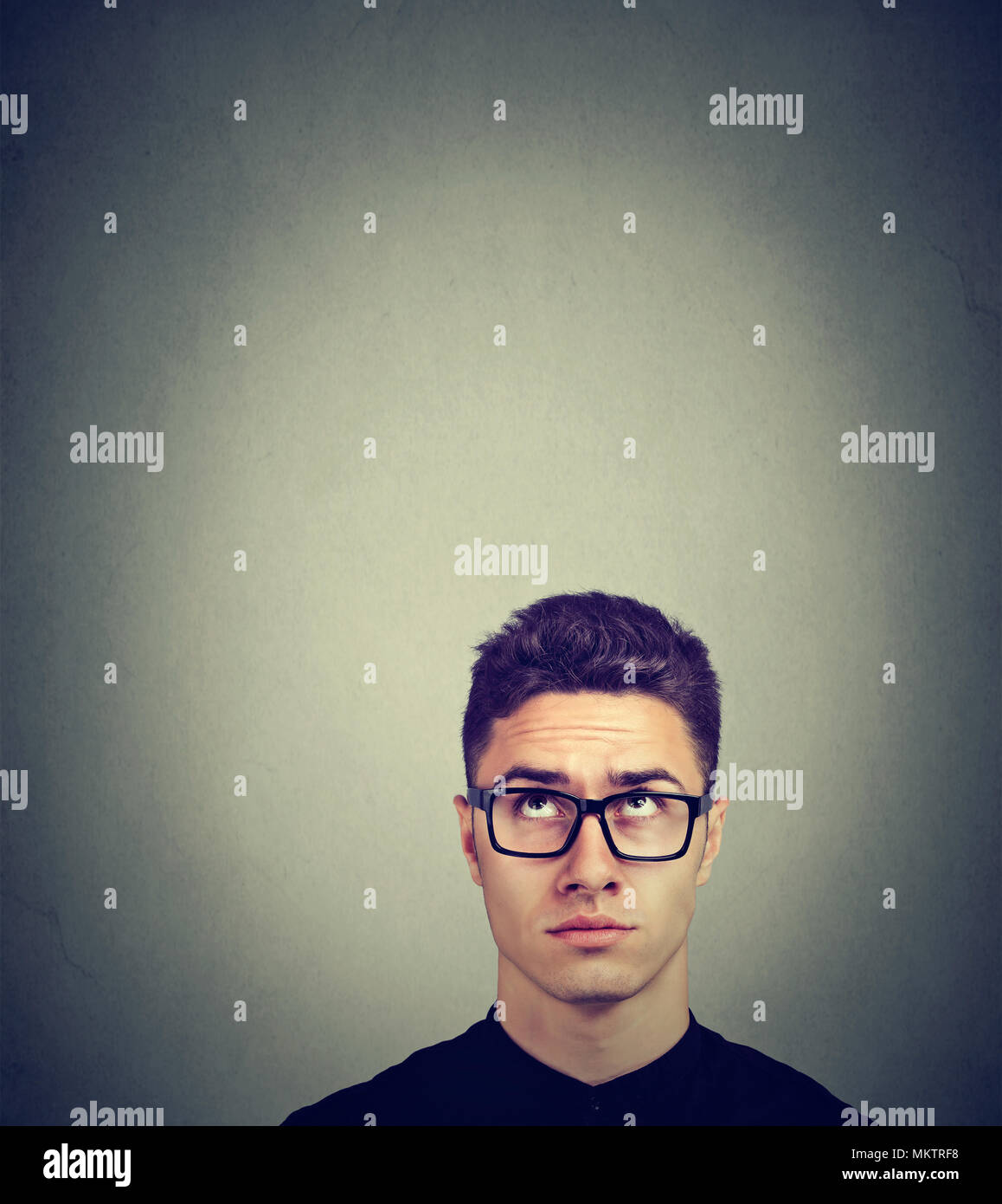 Doubtful man in glasses looking up Stock Photo - Alamy