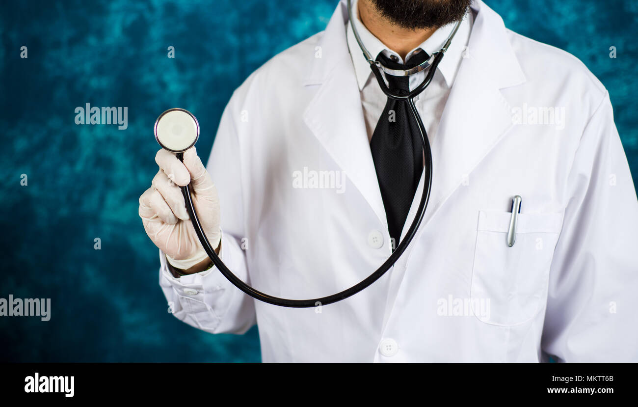 Doctor holding a stethoscope close up against blue background Stock ...
