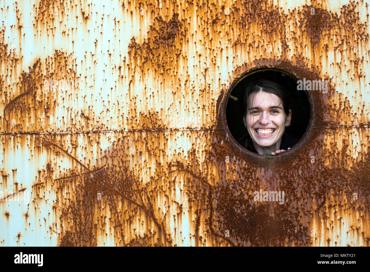 Young woman joyfully looks out of the window of an abandoned bunker ...