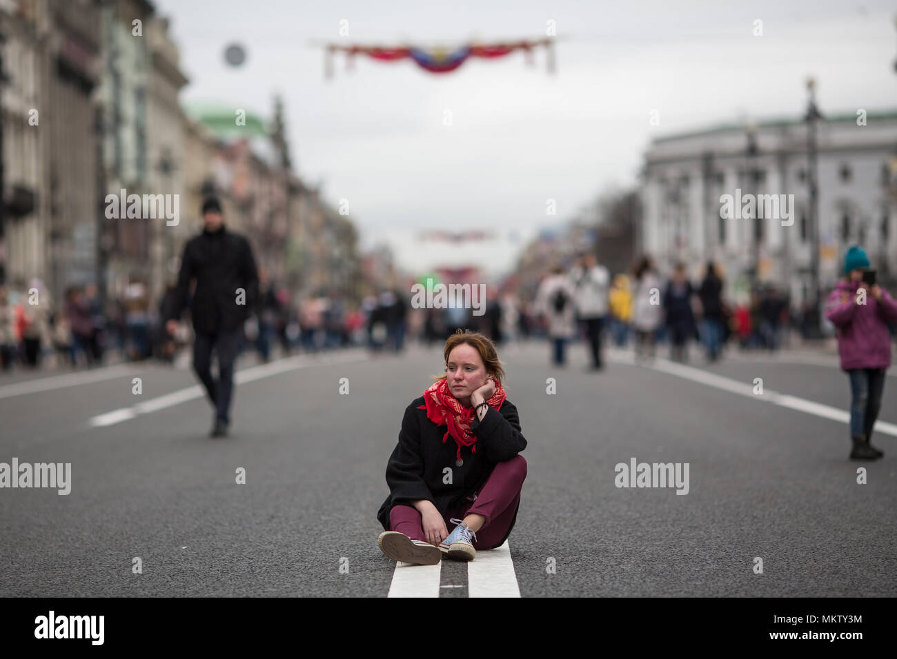 Cute girl sitting on the road in the middle of the busy street Stock ...