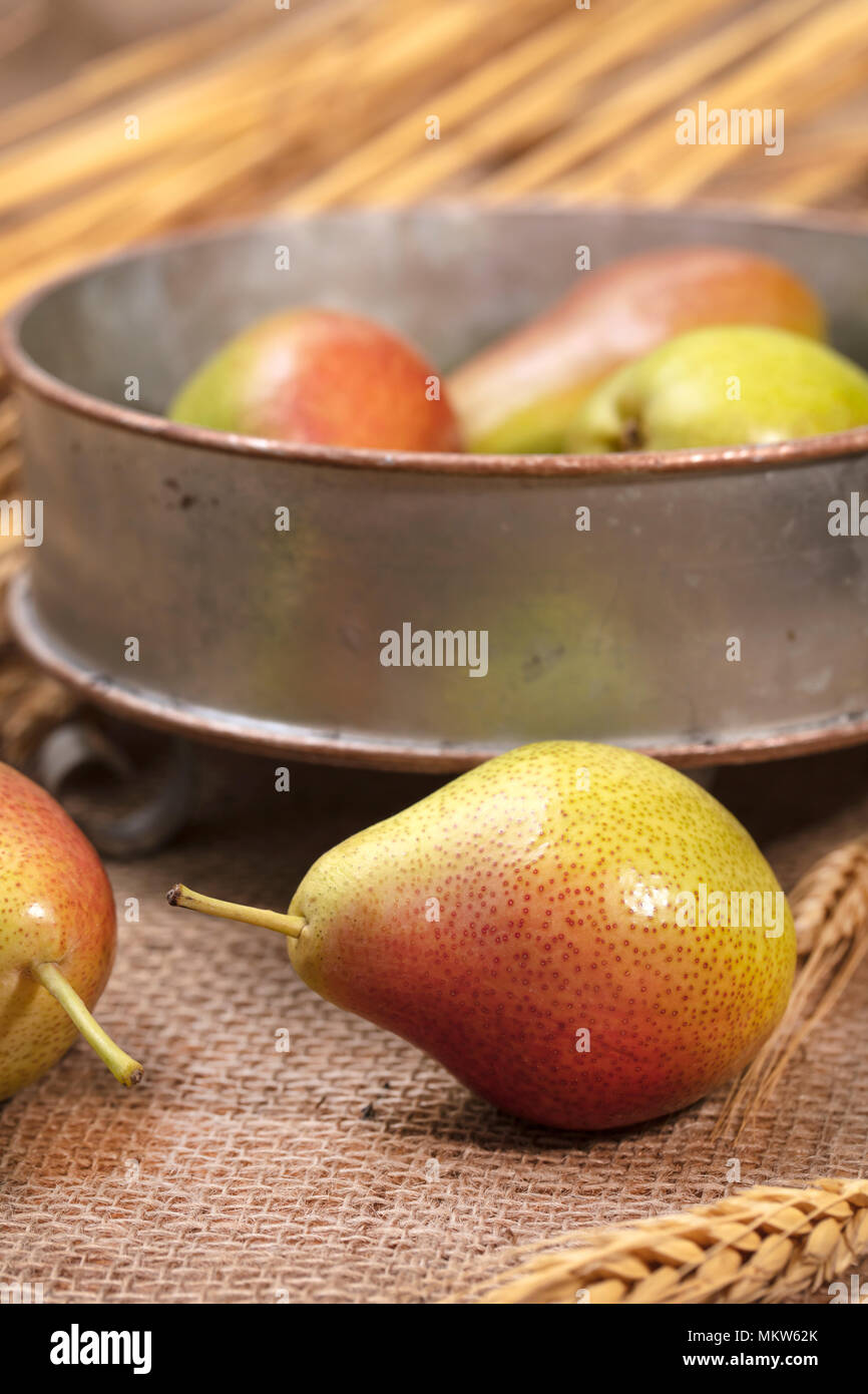 Yellow and red pears on burlap and in vintage pan decorated with wheat ...