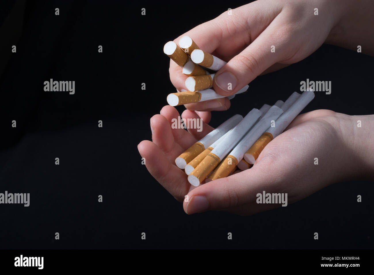 Hand is giving out bundle of cigarettes on black background Stock Photo ...