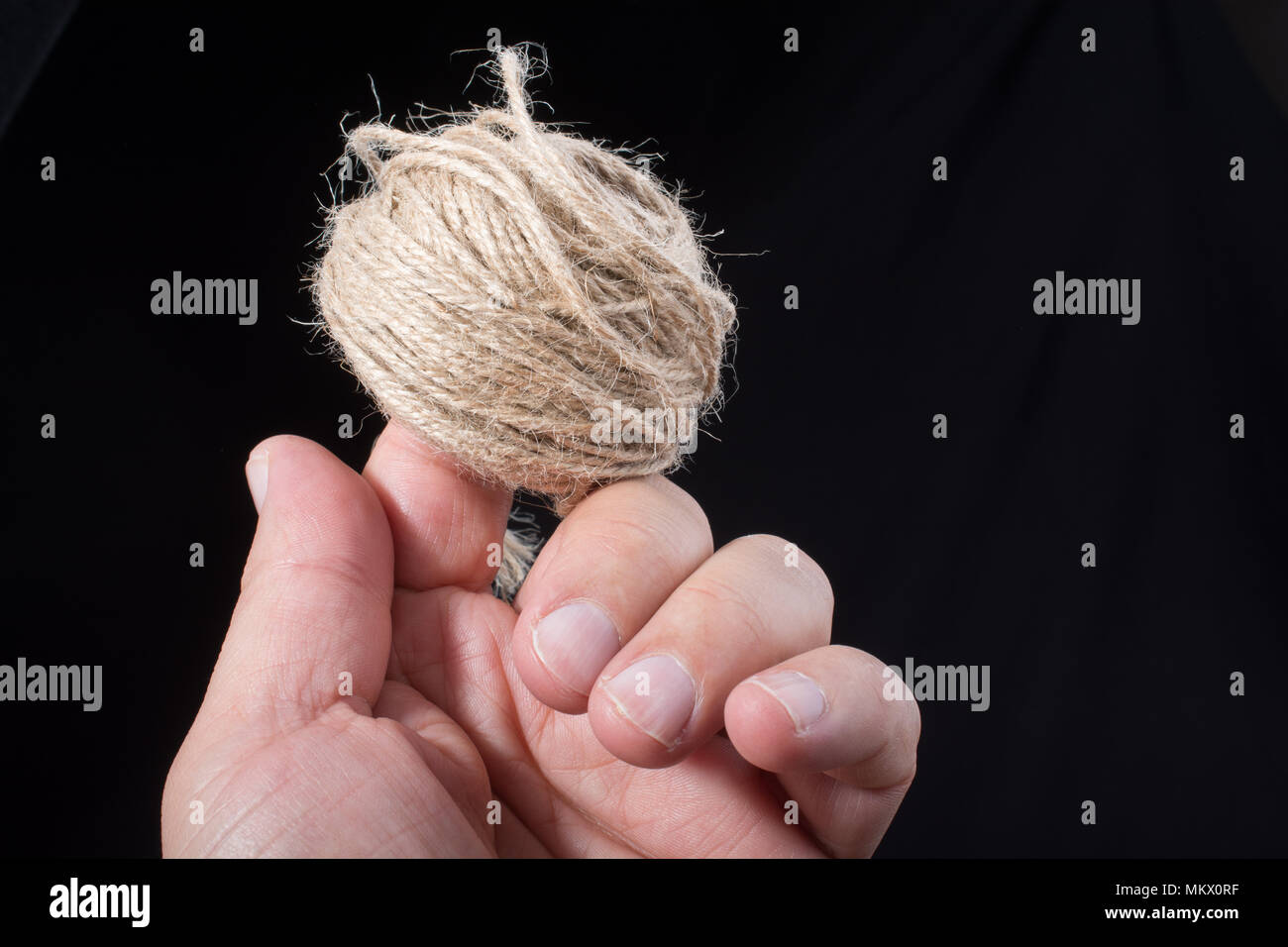 Spool of brown string in hand on black background Stock Photo - Alamy