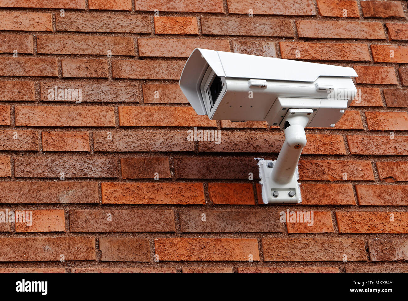 Side view of a surveillance camera on brick wall Stock Photo - Alamy