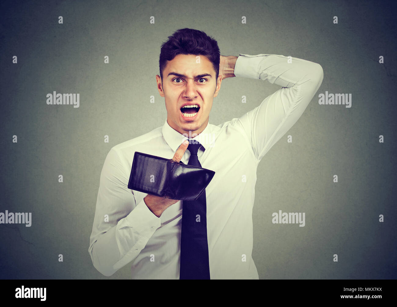 Portrait of a shocked, frustrated angry man, holding an empty wallet ...