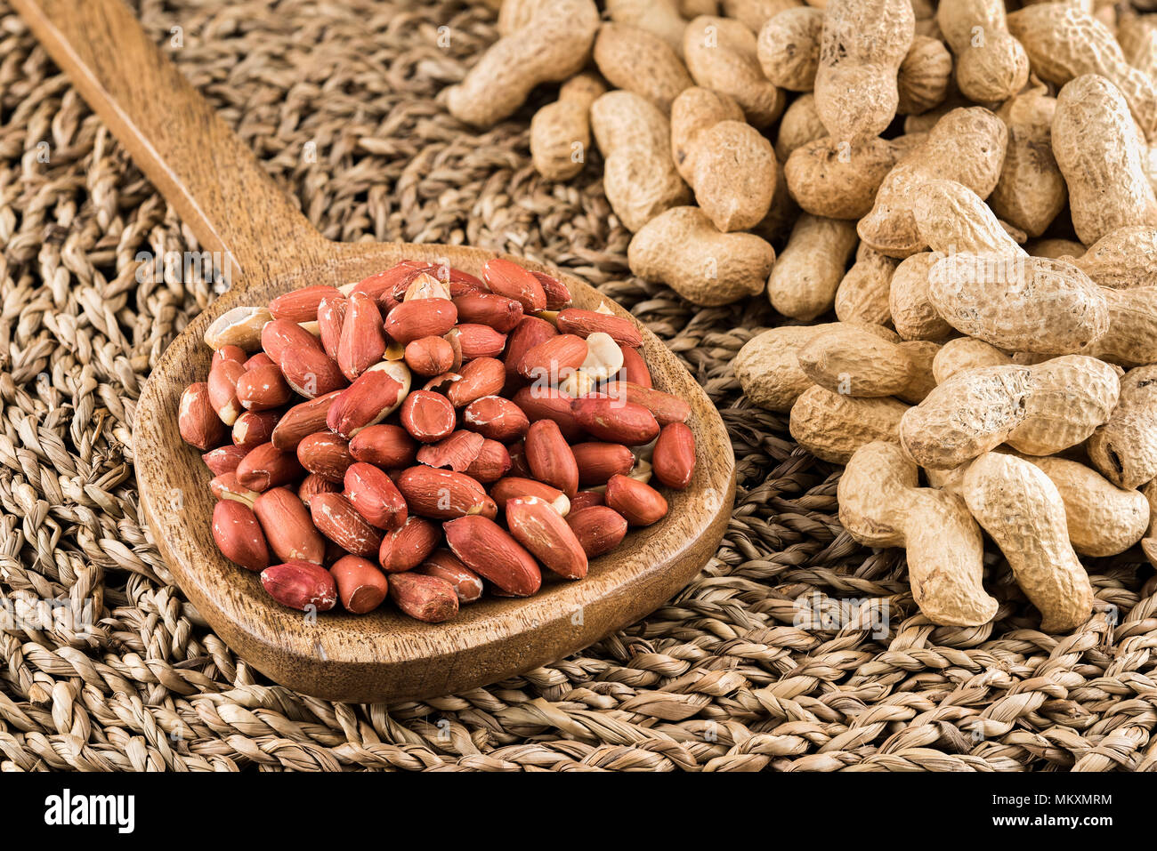 Peeled peanuts in a wooden ladle and peanuts in nutshell on natural ...