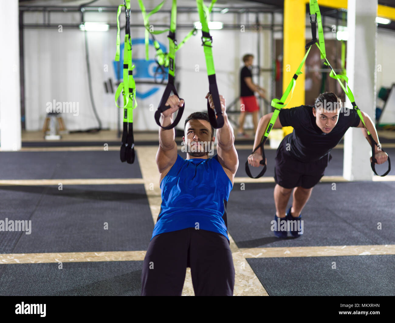 two young athlete men working out pull ups with gymnastic rings at the ...