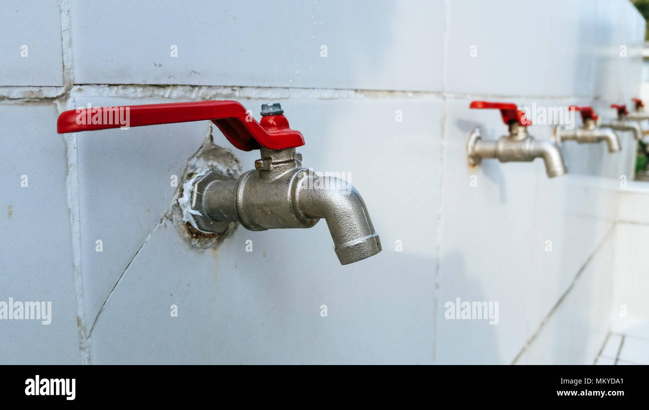 Steel water spout with red handle Stock Photo - Alamy