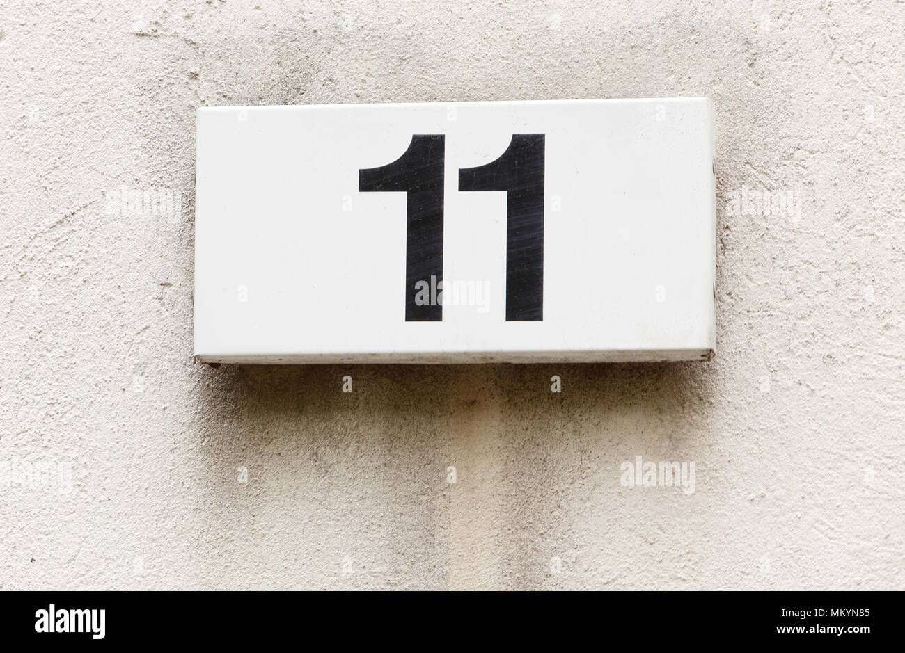 Number eleven on a white plate attached to a buildings exterior wall ...