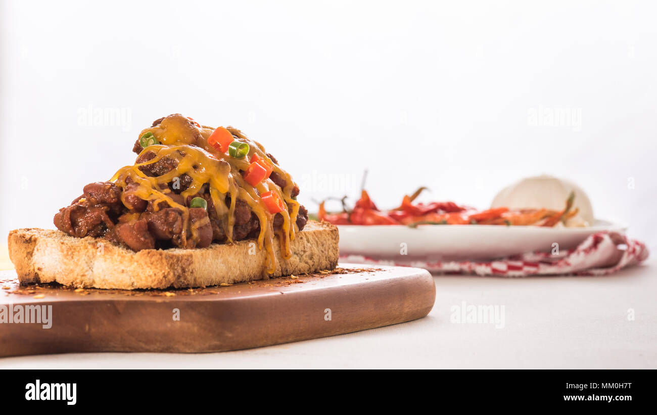 Spicy beef and bean chili on toast covered in melted cheddar cheese ...