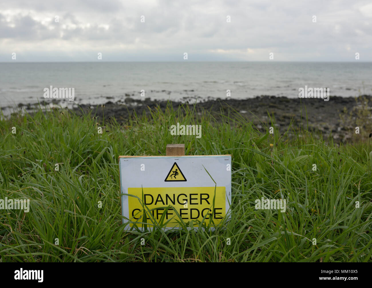 Yellow and white Danger cliff edge warning sign on wales coast path ...