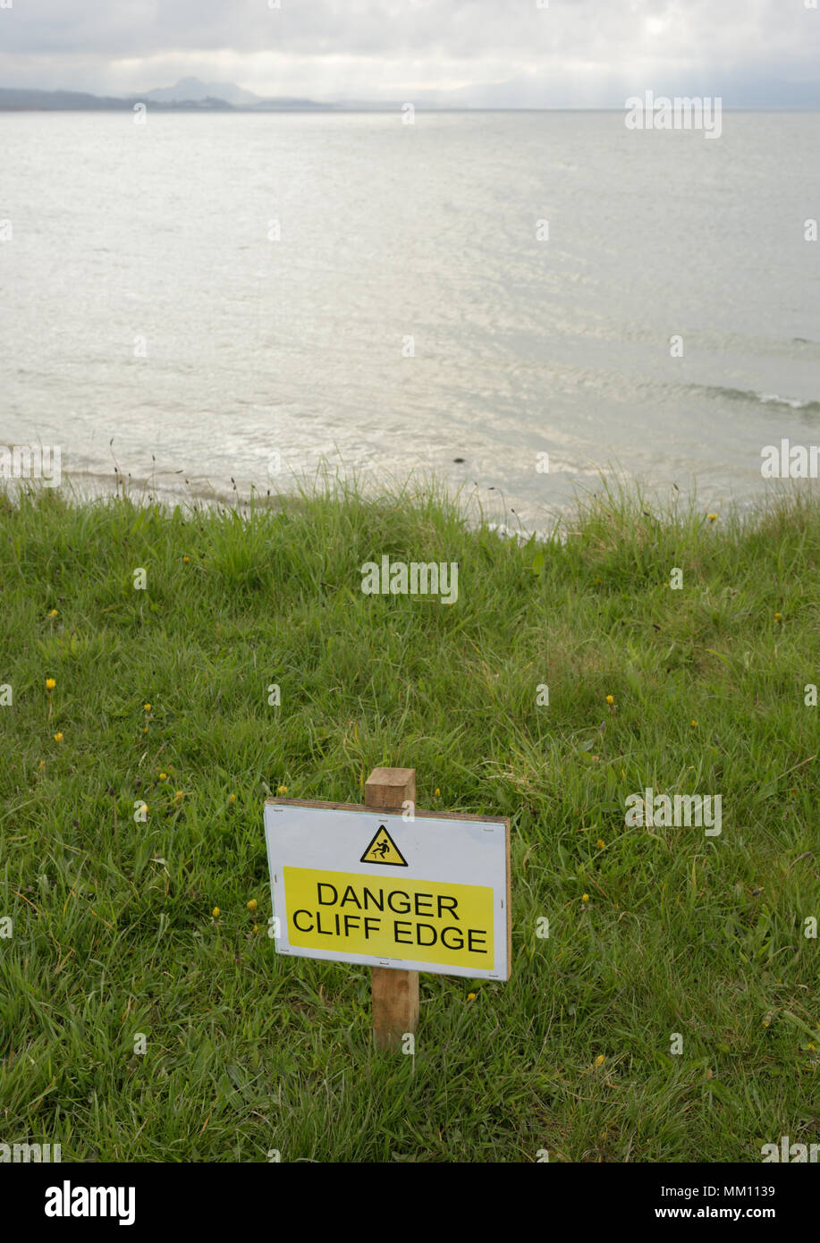 Yellow and white Danger cliff edge warning sign on wales coast path ...