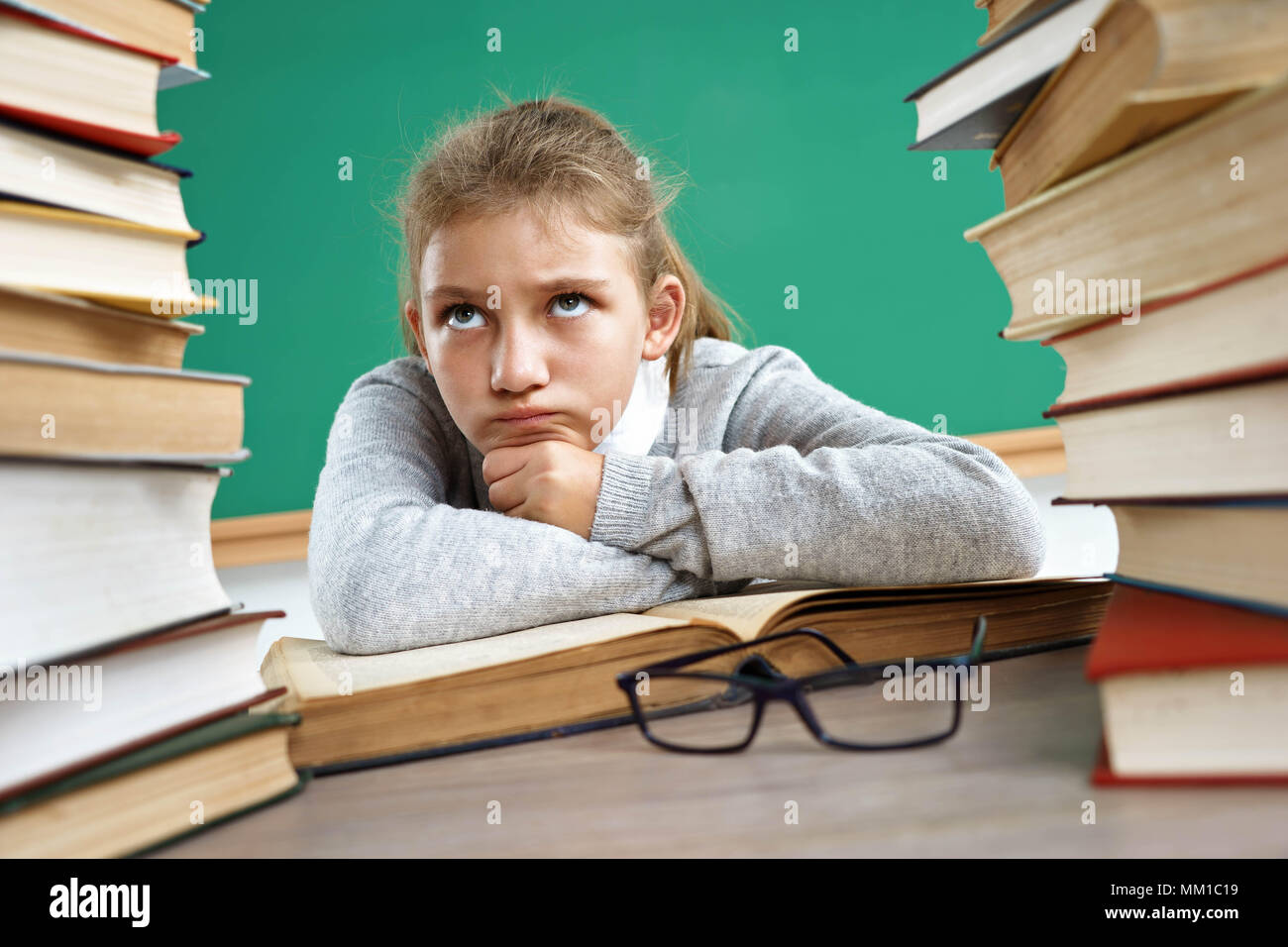 Boredom. Litlle schoolgirl rested her chin on her hands, laying them on ...