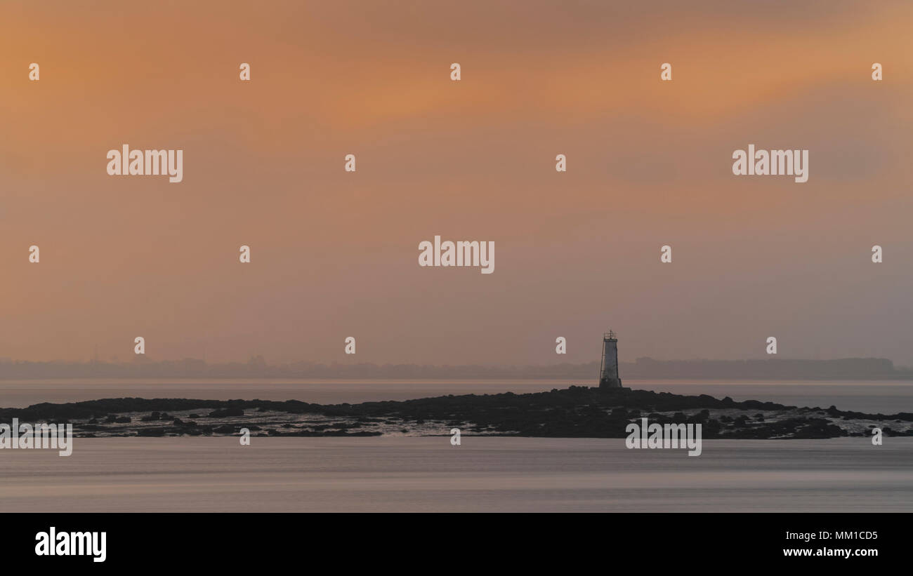 Image of lighthouse off the coast taken at sunrise. Morning glow. light ...