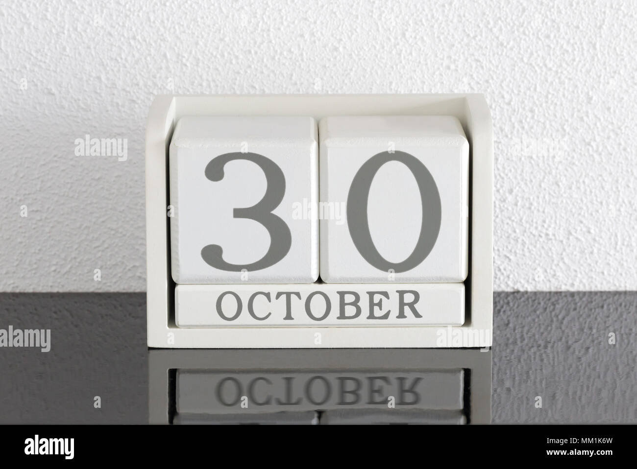 White block calendar present date 30 and month October on white wall ...