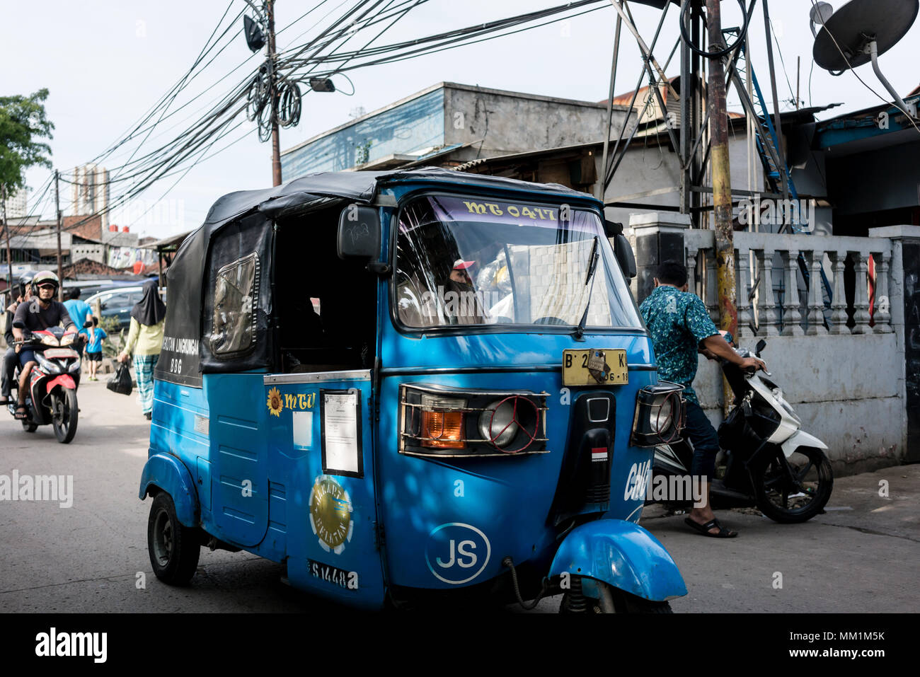 Blue auto rickshaw on a narrow and crowded road in a poor village in ...
