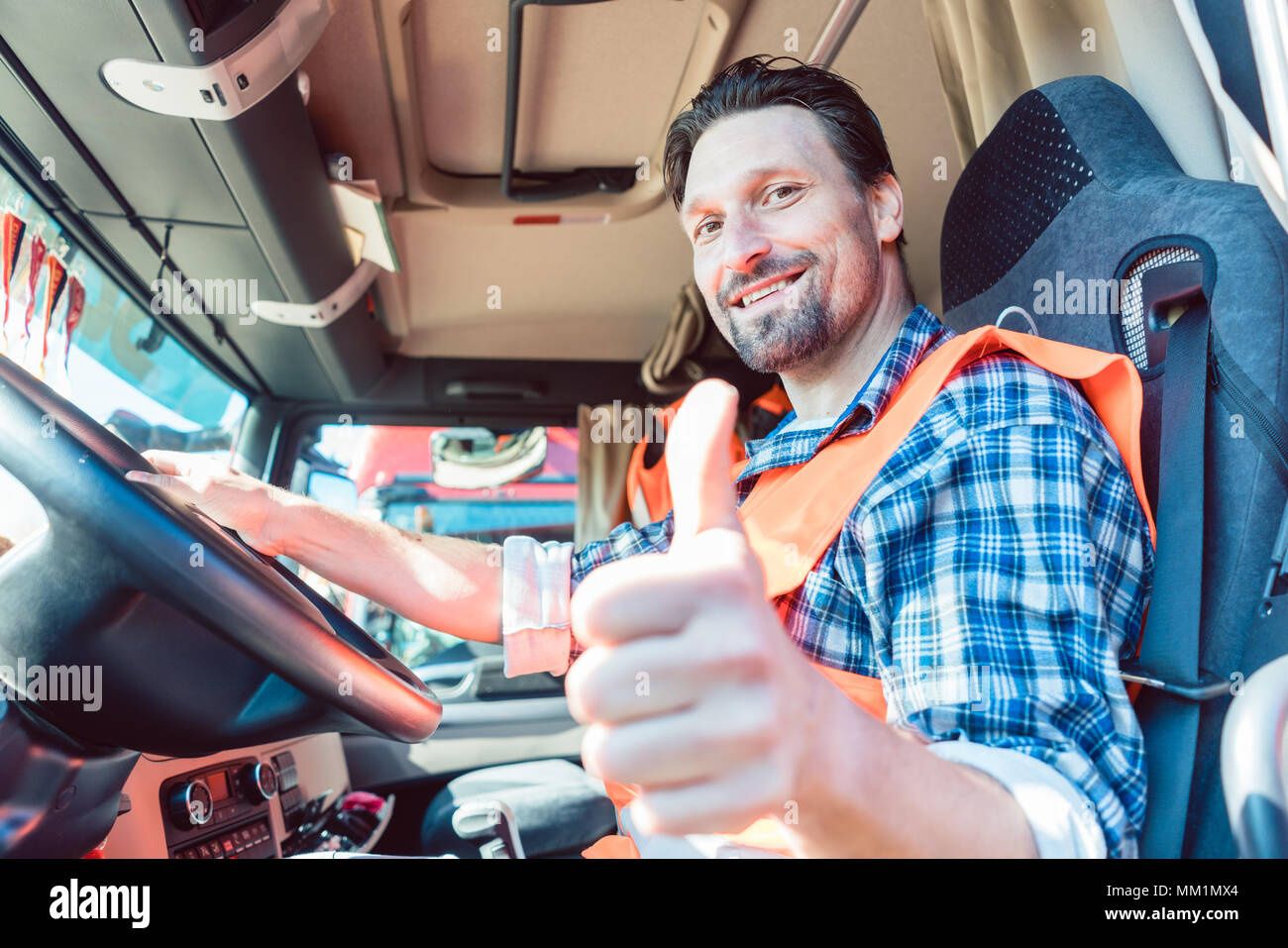 Truck driver sitting in cabin giving thumbs-up Stock Photo - Alamy