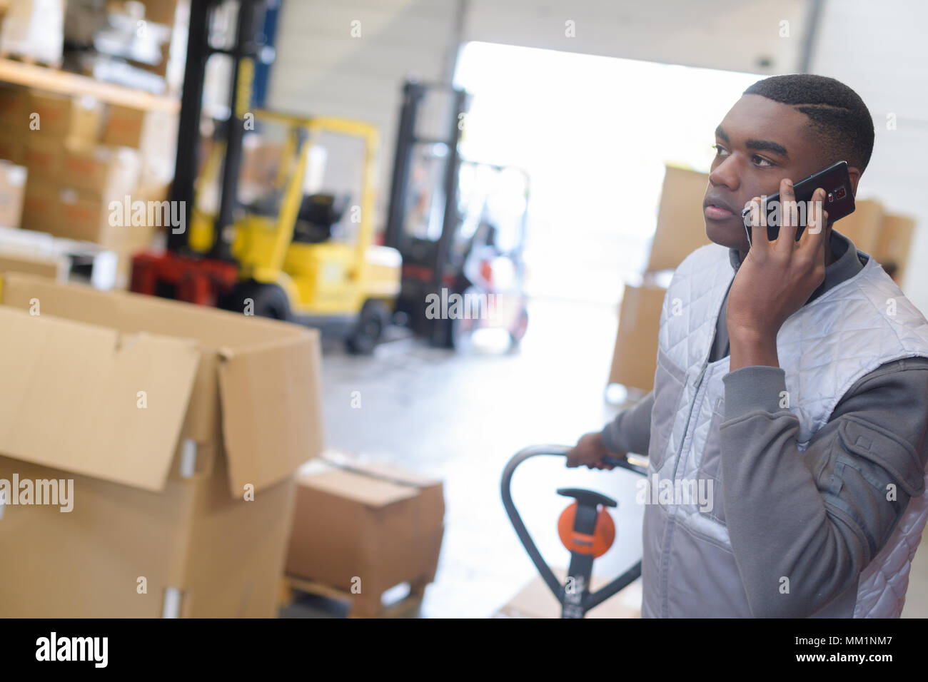 Warehouse worker using mobile phone Stock Photo - Alamy