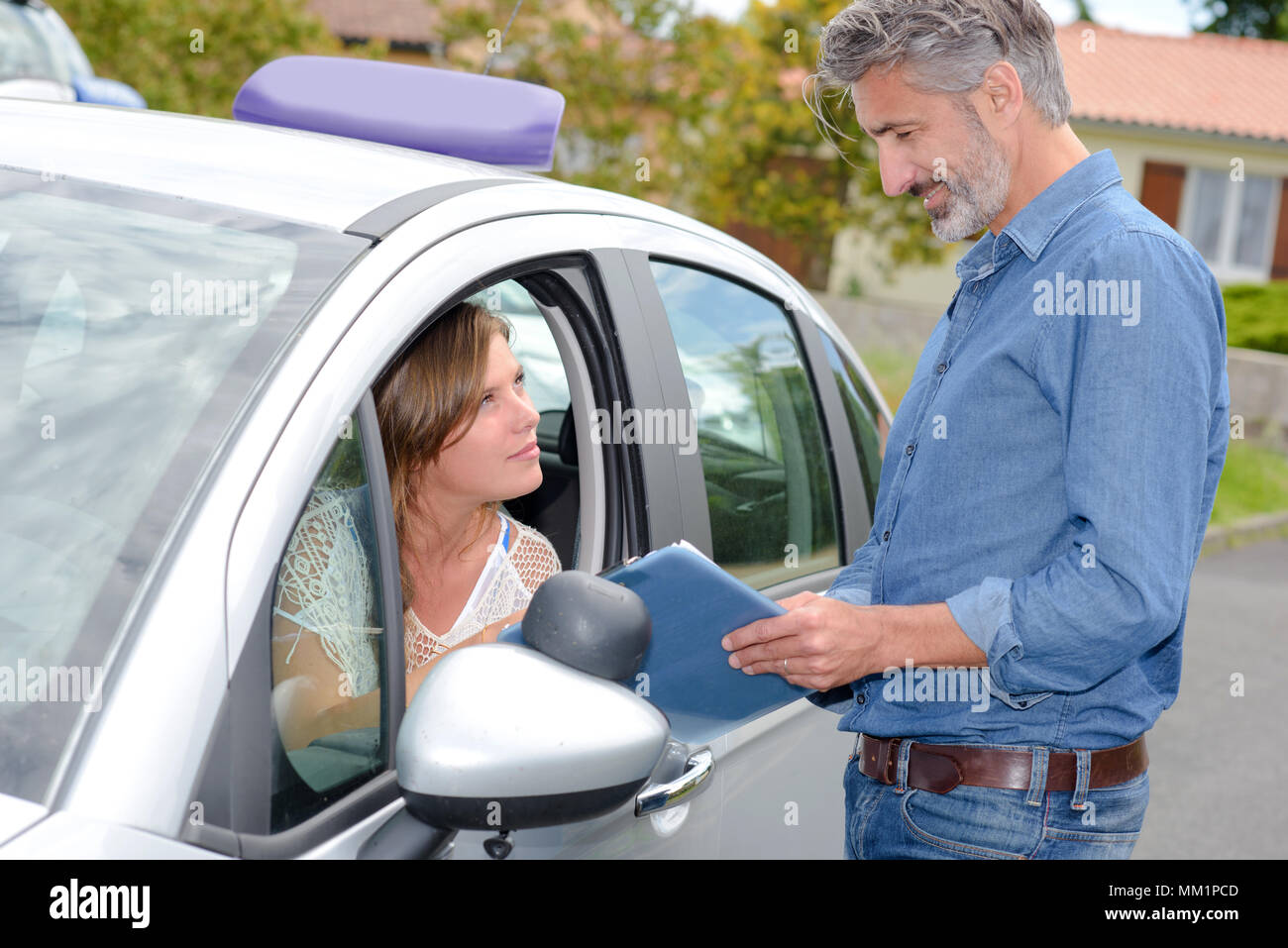 Learner driver looking out of car window talking to instructor Stock ...