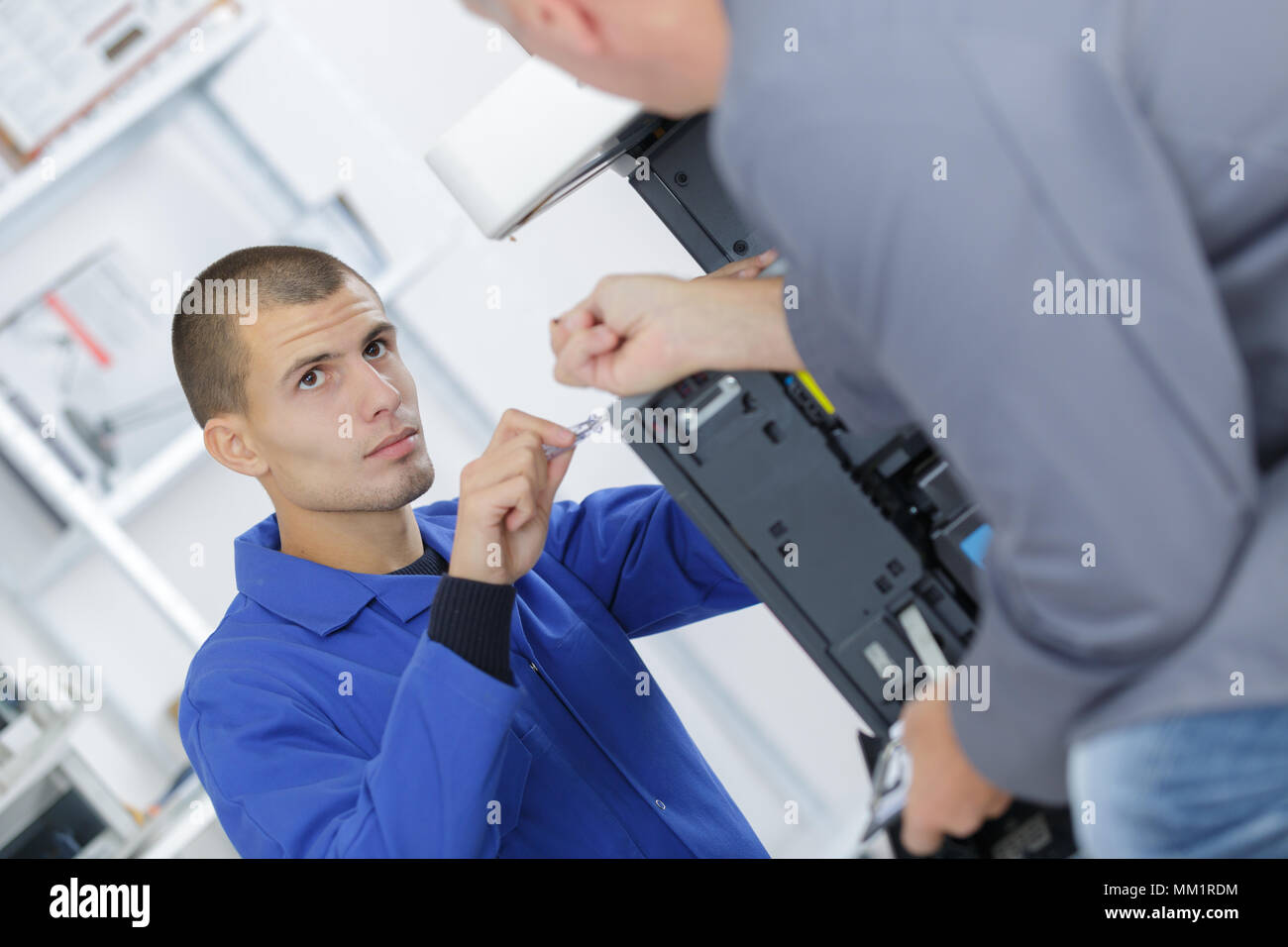 closeup shot young male technician repairing digital photocopier ...
