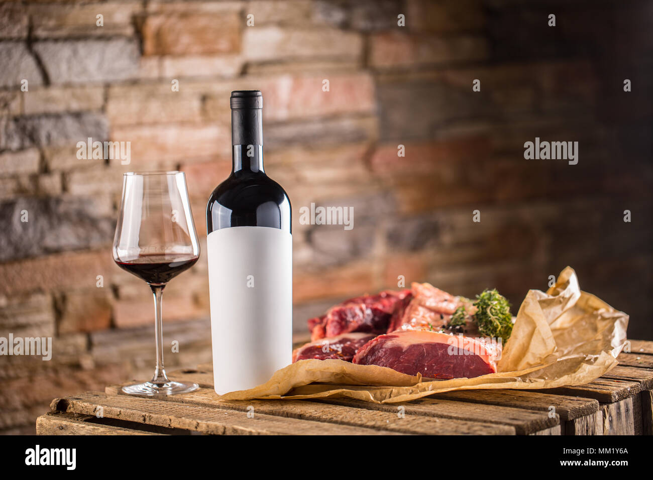 Cup and a bottle of red wine and raw beef steak on wooden table Stock ...