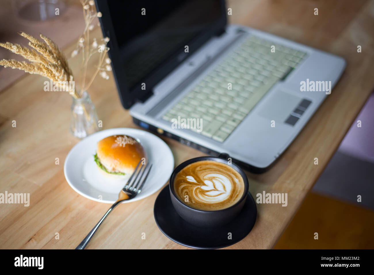 Coffee and mini hamburger on wood table with laptop computer in coffee ...