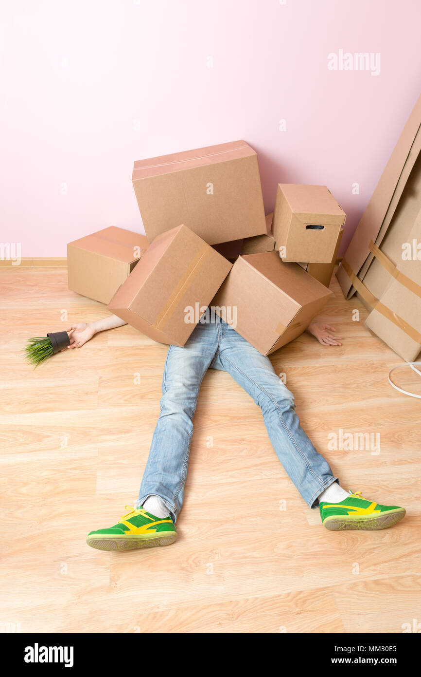 Photo of man in jeans and sneakers lying under cardboard boxes Stock ...