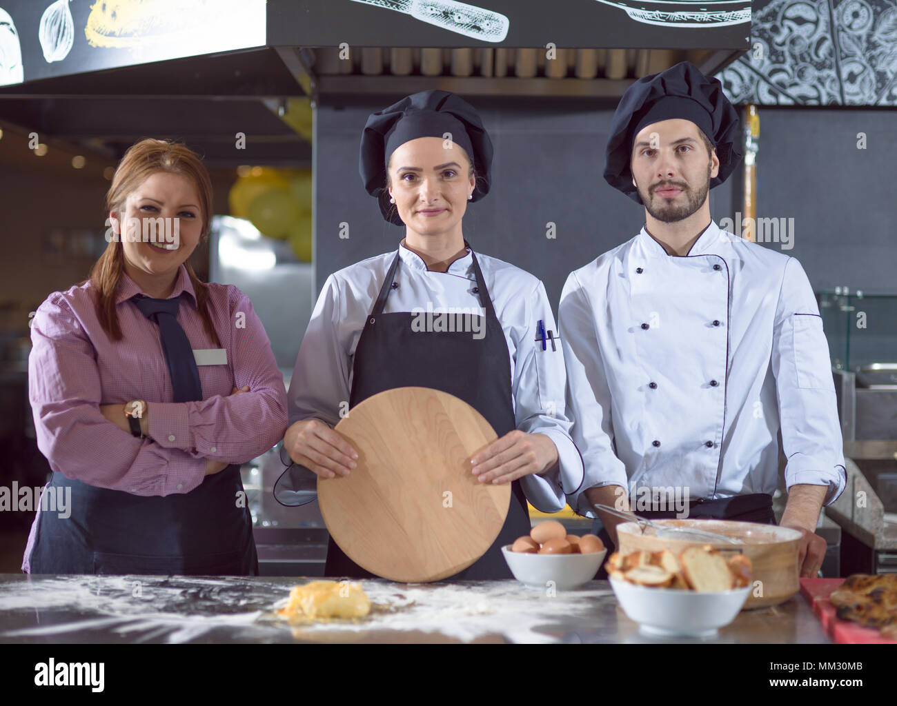 Portrait of group chefs standing together in commercial kitchen at ...