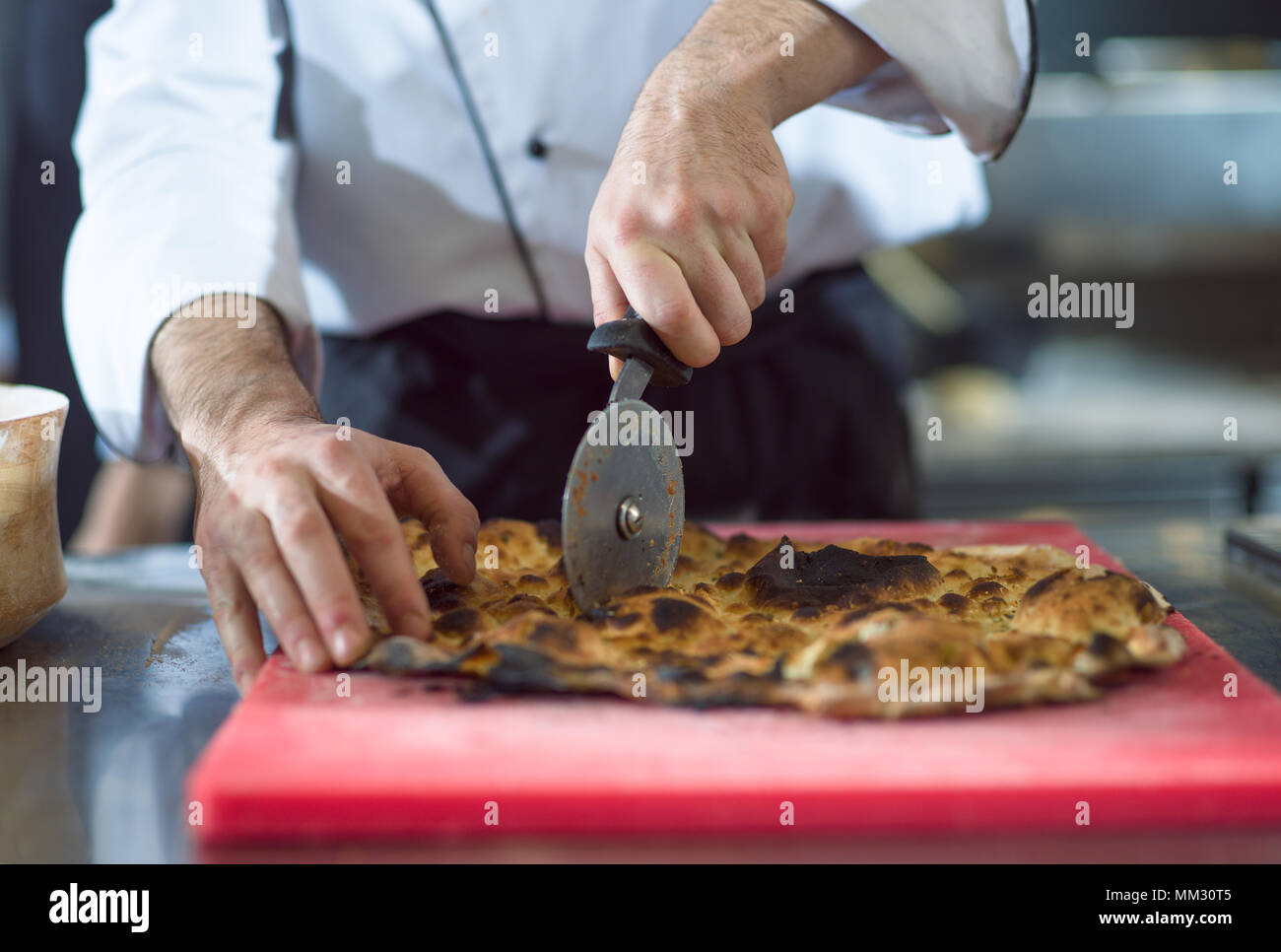 chef hands cutting baked bread out of the oven in a restaurant kitchen ...