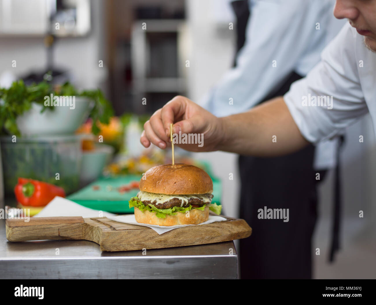 master chef putting toothpick on a burger in restaurant kitchen Stock ...