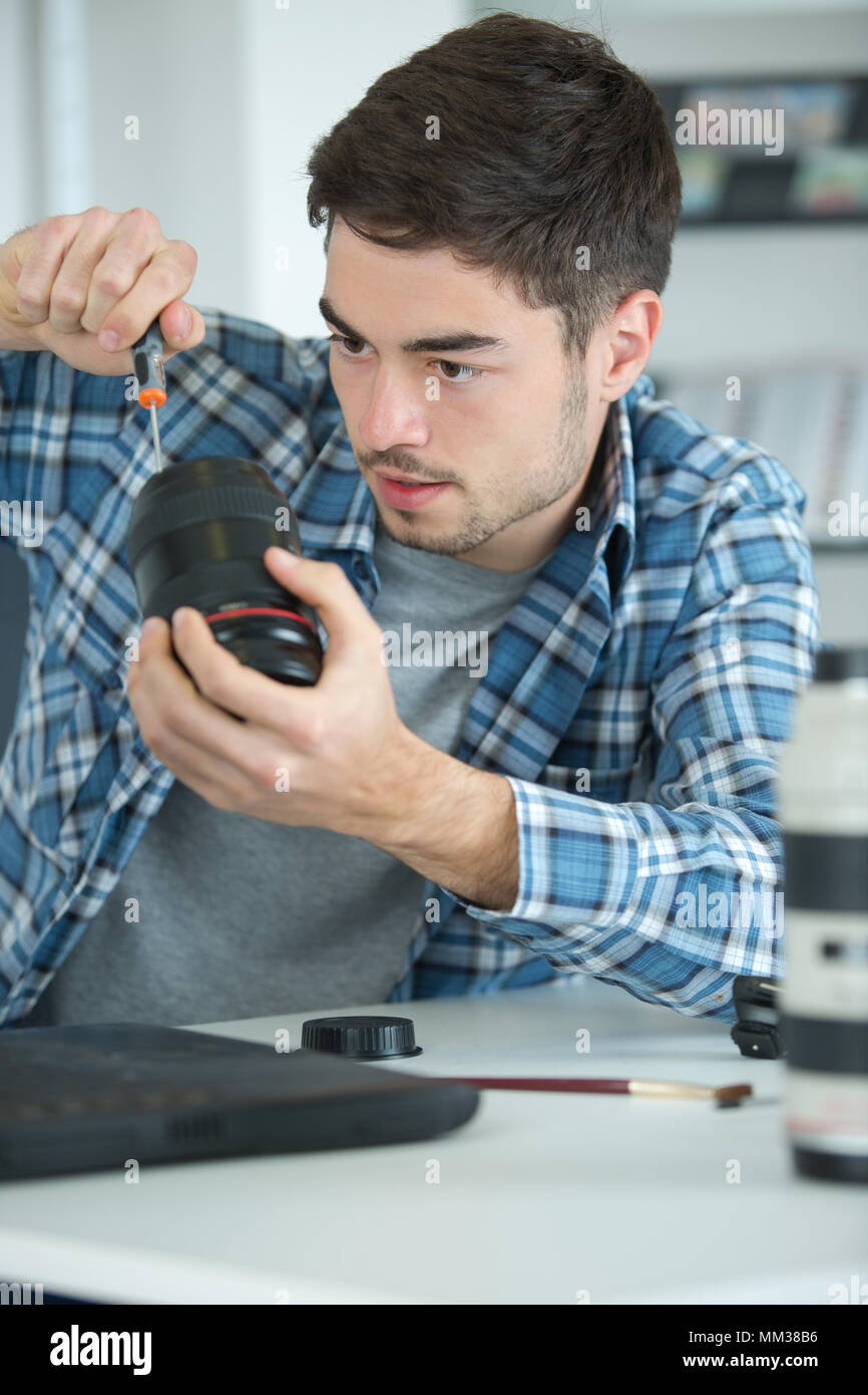 man fixing photo camera lens on an office table Stock Photo - Alamy