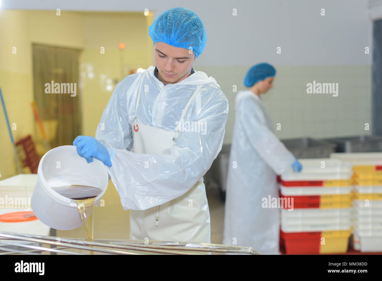 Factory worker pouring liquid from bucket Stock Photo - Alamy